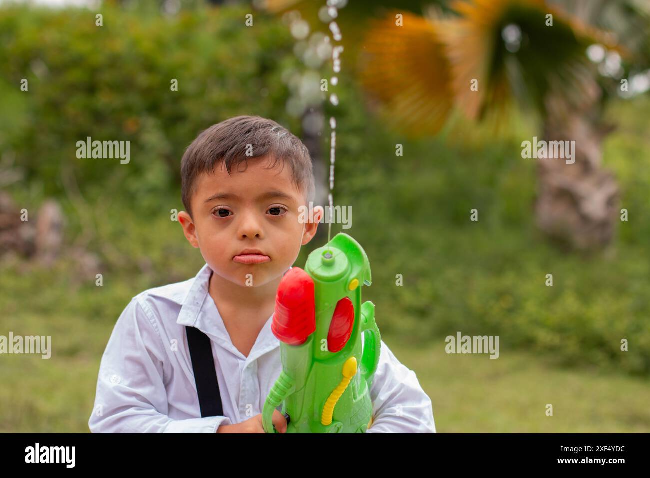 lifestyle, child with down syndrome plays with water pistol and has fun ...