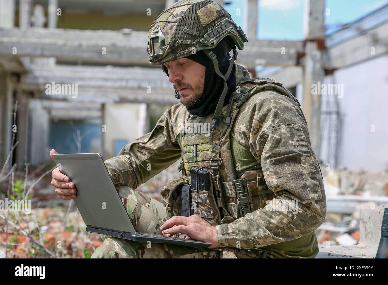 Military mission. Soldier in uniform using laptop near abandoned ...