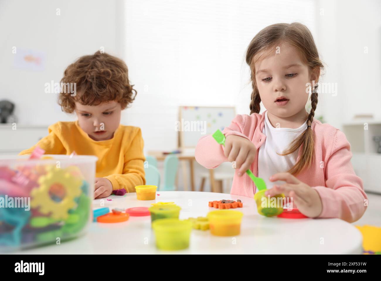 Cute little children modeling from plasticine at white table in ...