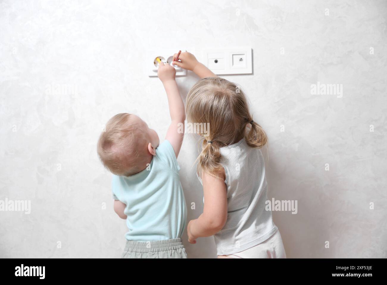 Little children playing with electrical socket indoors, back view ...