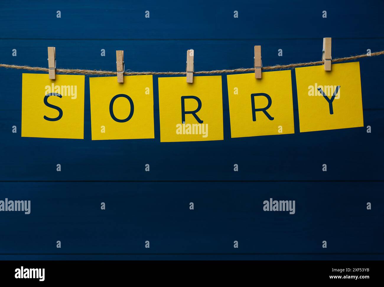 Word Sorry made of yellow paper notes with letters hanging on rope ...