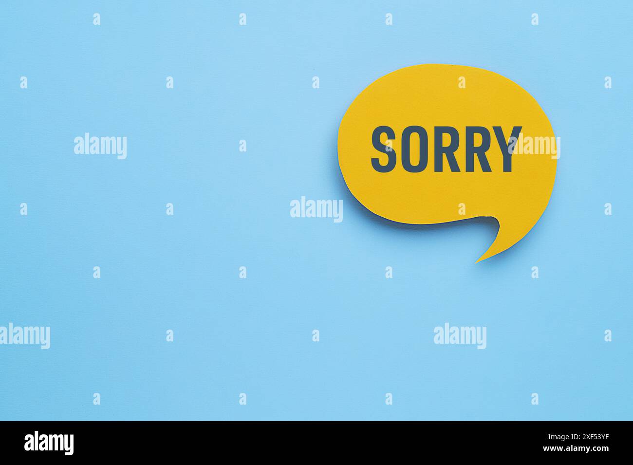 Yellow paper speech balloon with word Sorry on light blue background ...