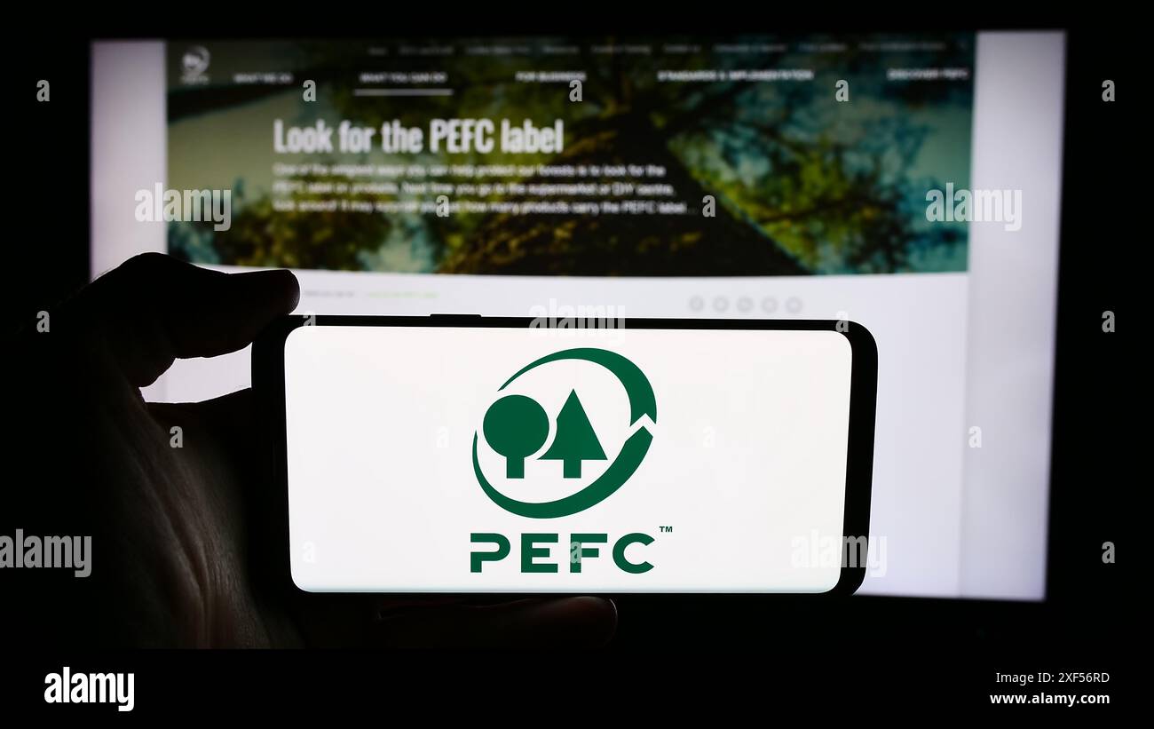 Person holding cellphone with logo of Programme for the Endorsement of ...