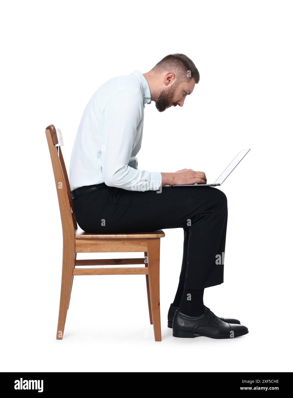 Man with poor posture sitting on chair and using laptop against white ...