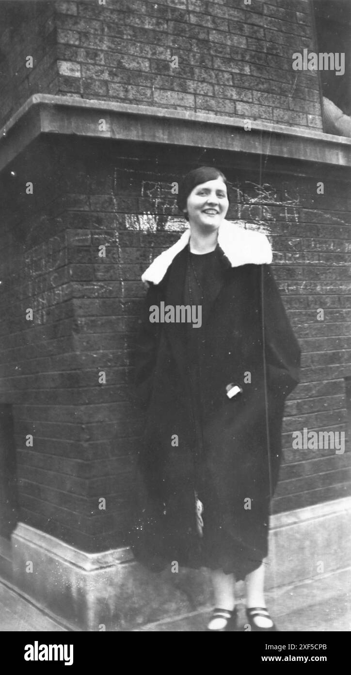 Fashion: A lady in a dark coat standing beside a building. From a ...