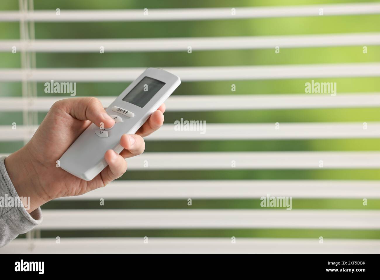 Man using remote control to adjust window blinds indoors, closeup ...