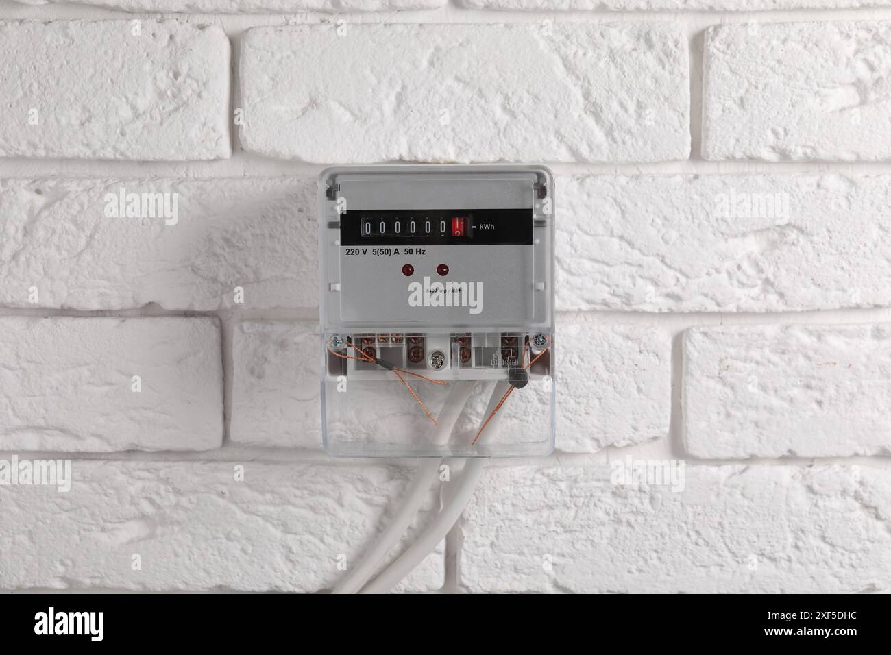 Electric meter on white brick wall. Energy measuring device Stock Photo ...