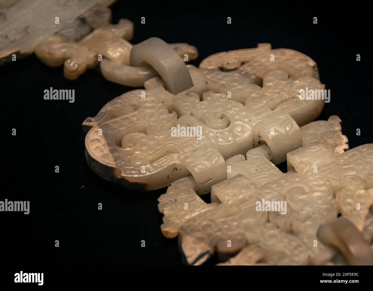 A Chinese jade artifact with exquisite patterns against black ...