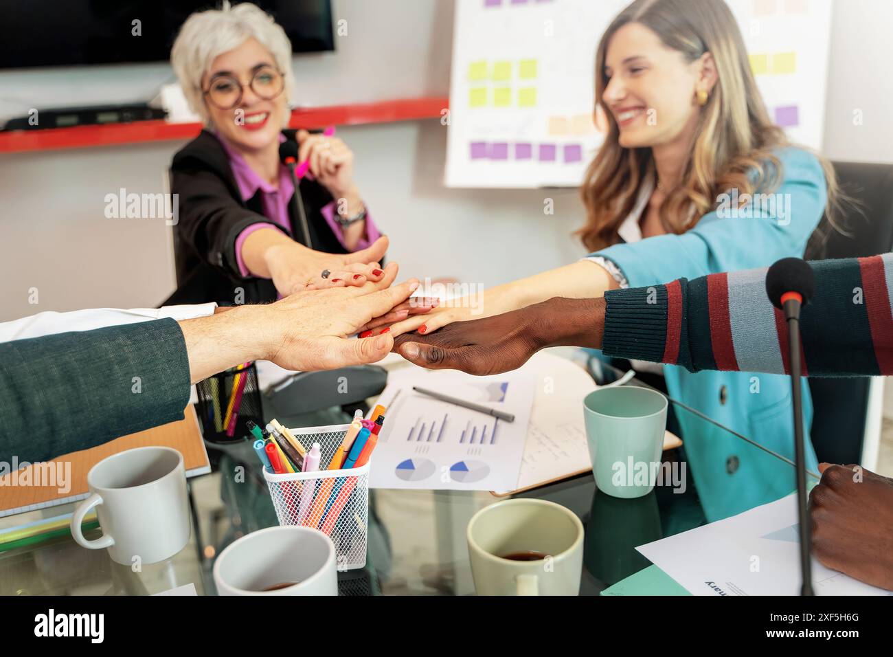 Diverse business team putting hands together in unity - professional collaboration, teamwork and ...