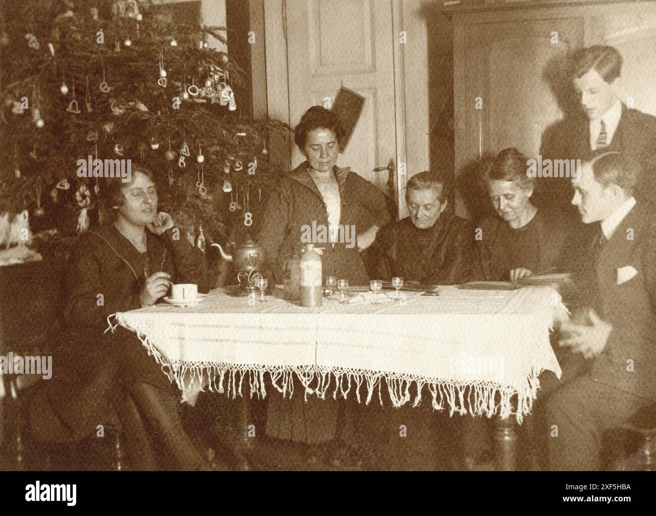 Germany. 1920s. A family gathered around a table looking through ...