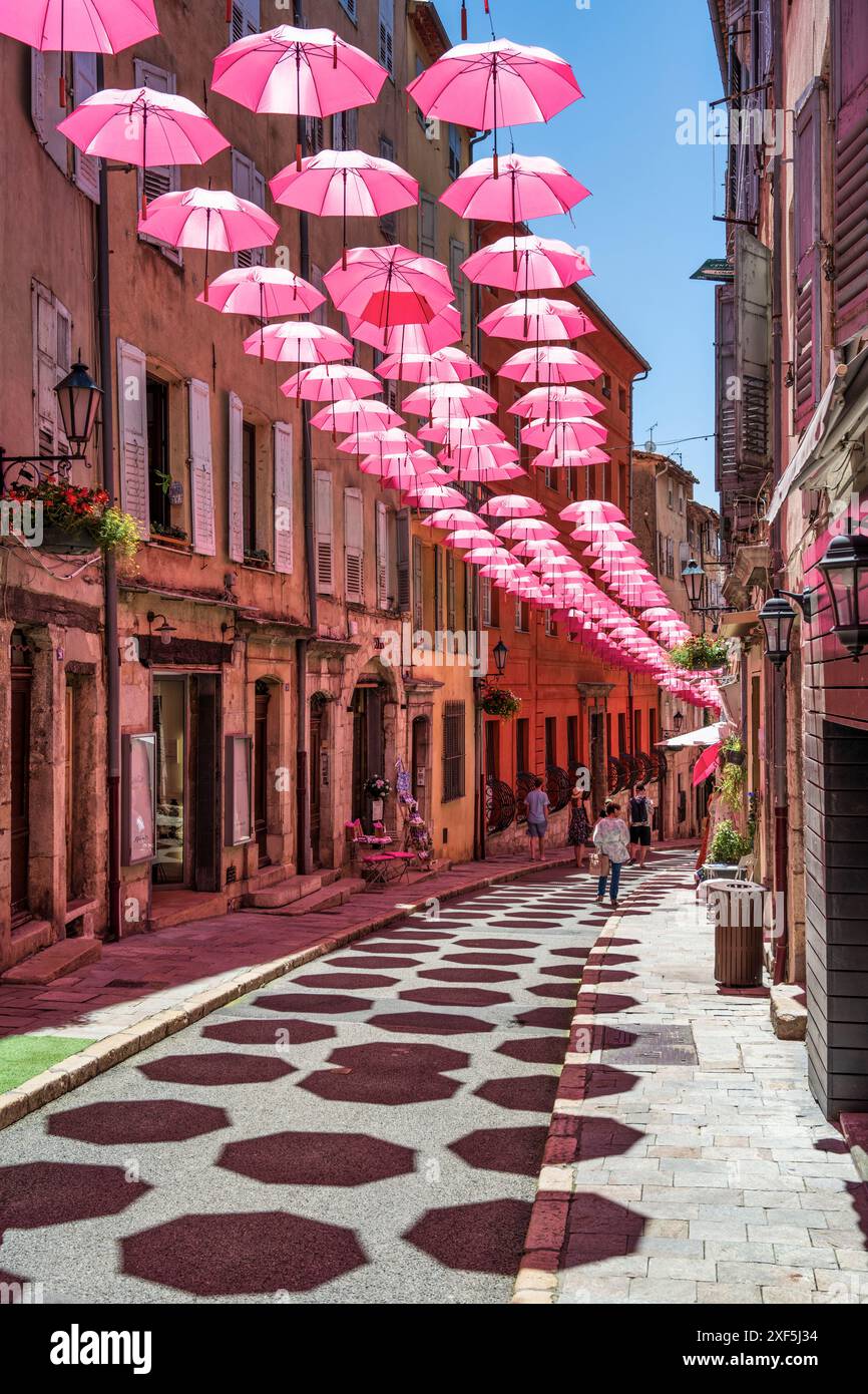 Floating pink umbrellas suspended above Rue Amiral de Grasse in old ...