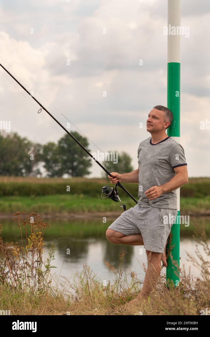Portrait of a man in nature with a fishing rod. Fishing near the water ...