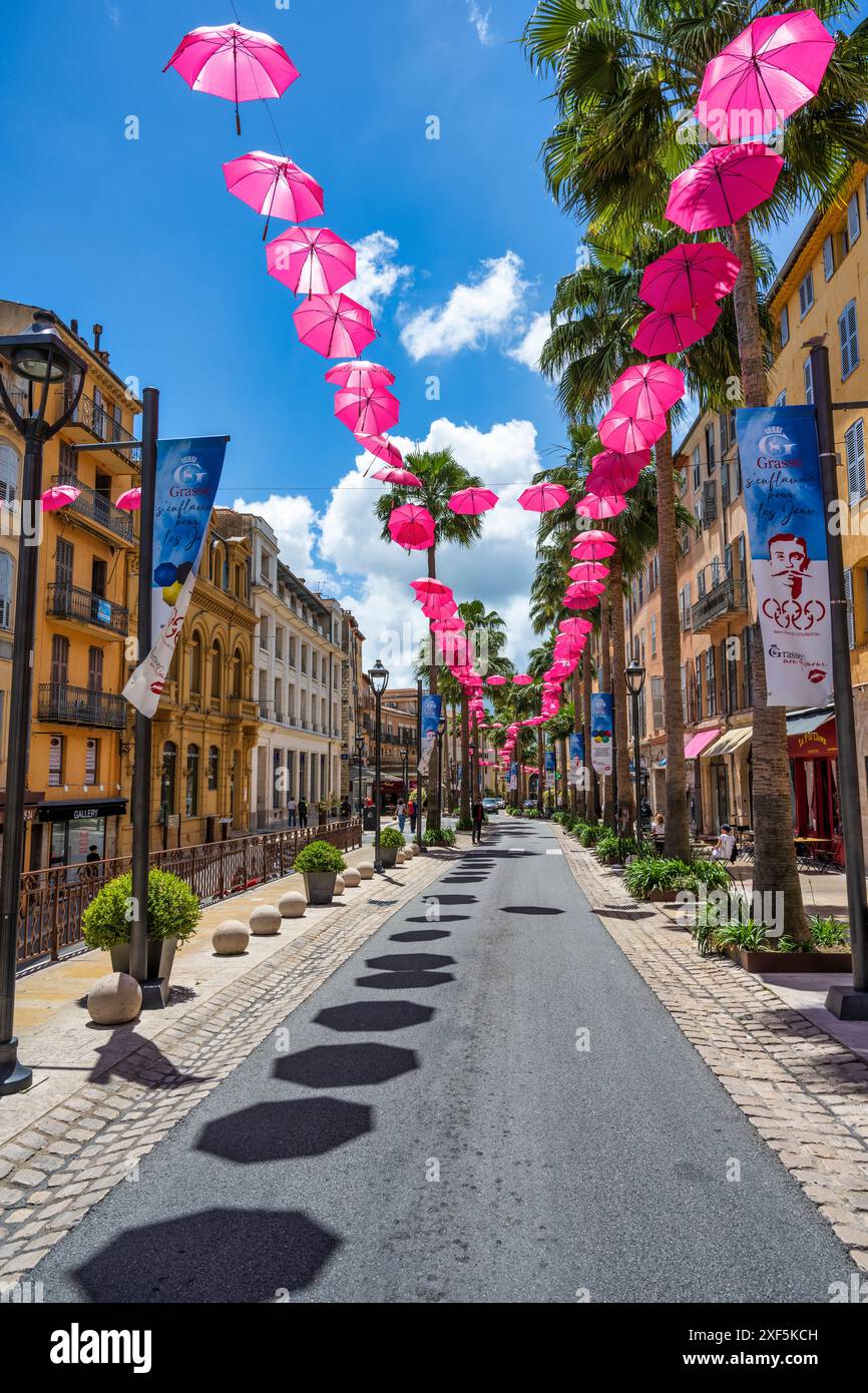 Street lined with floating pink umbrellas in old town of Grasse on the ...