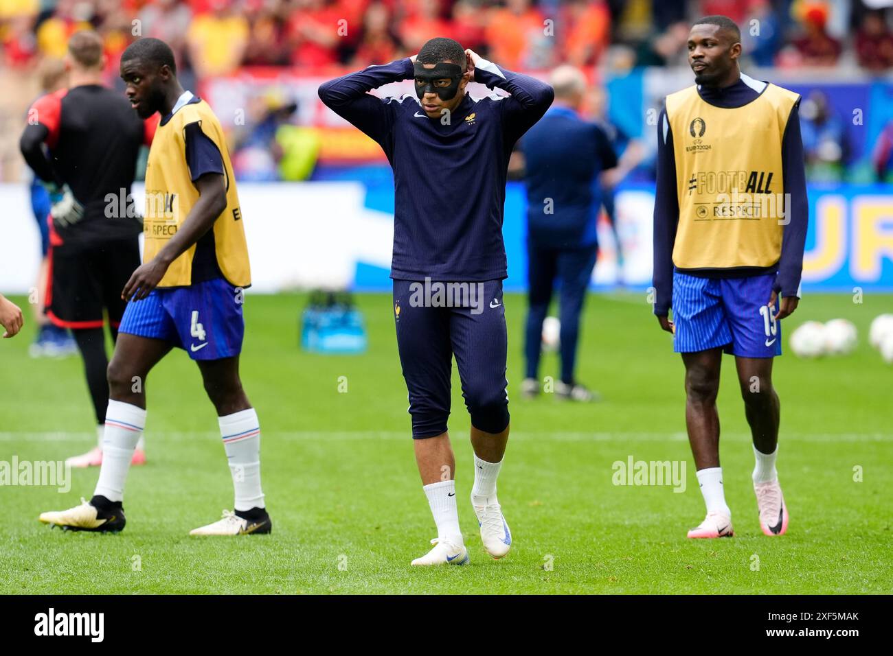 France's Kylian Mbappe (centre), wearing a protective mask, warms up ...