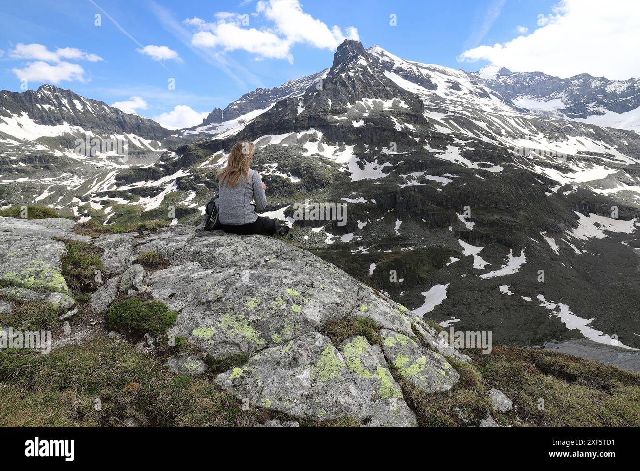 A woman rests on a rocky plateau in the Hohe Tauern National Park in ...