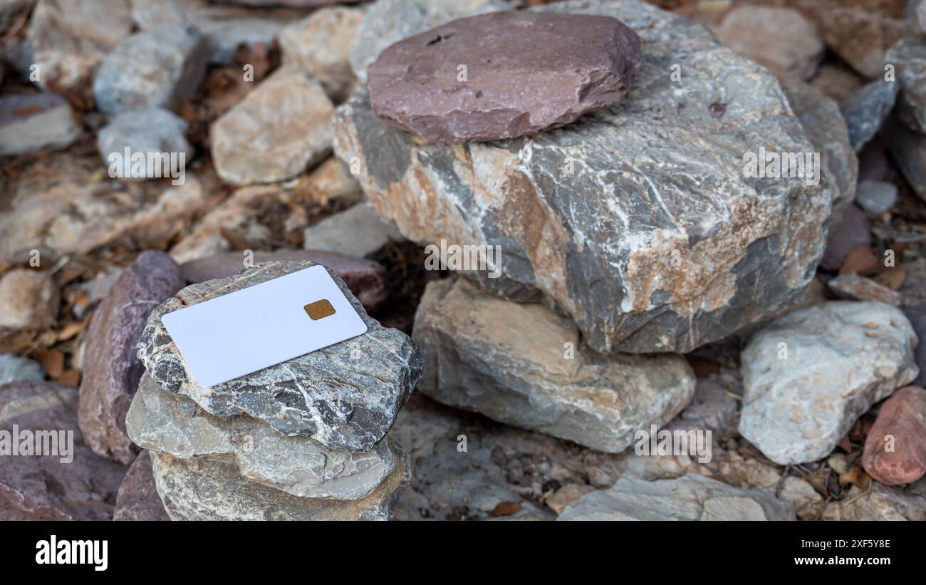 A white bank card lies on the rocks personifying the stability of the ...