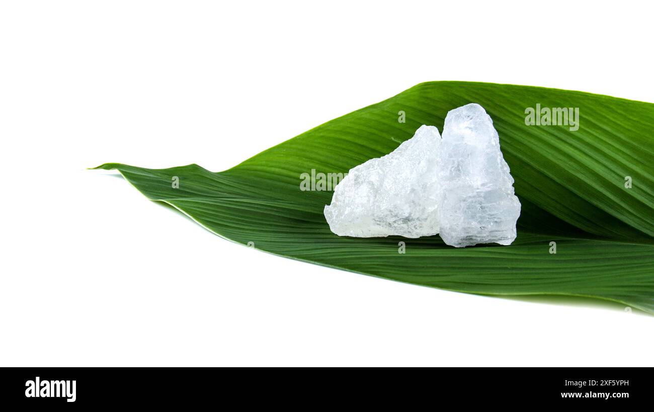 White crystal clear alum cube on green leaf isolated on white ...