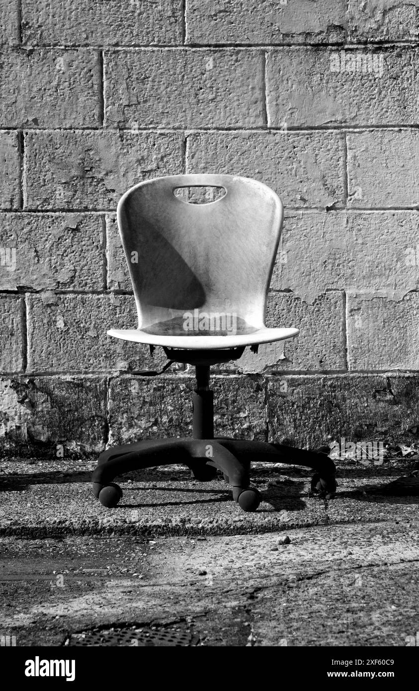 Roller style, desk chair sits abandoned besides a grungy, cinder block ...