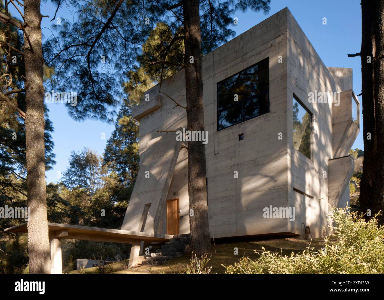 Corner elevation of irregular concrete facade and house entrance. Casa ...