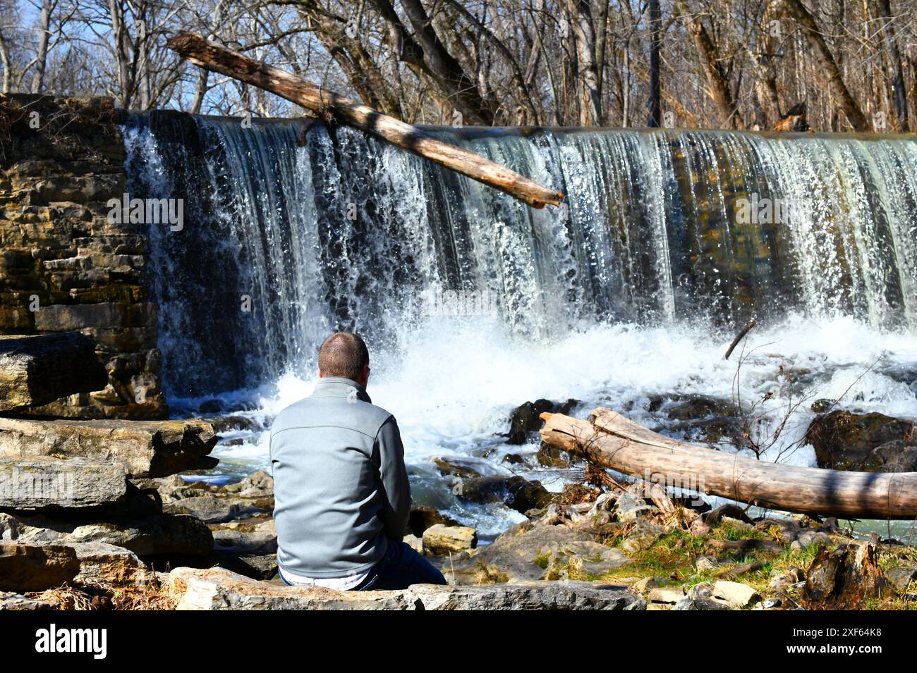 Visitor to the Amis Mill Ruins and Dam, Sits and watches the water spill over the dam. He is ...