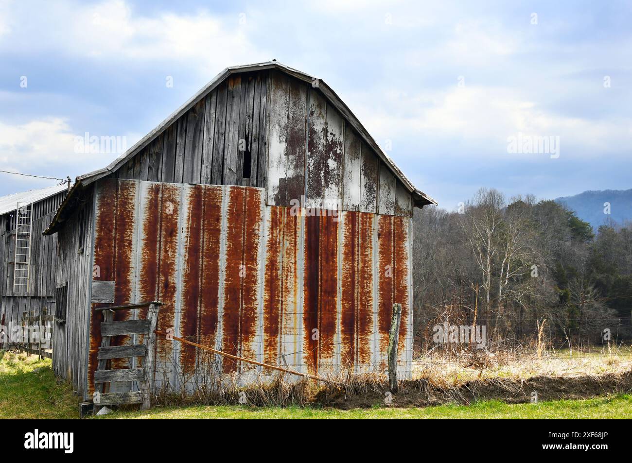 Old wooden barn, in Tennessee, has been repaired with tin. Boards are ...