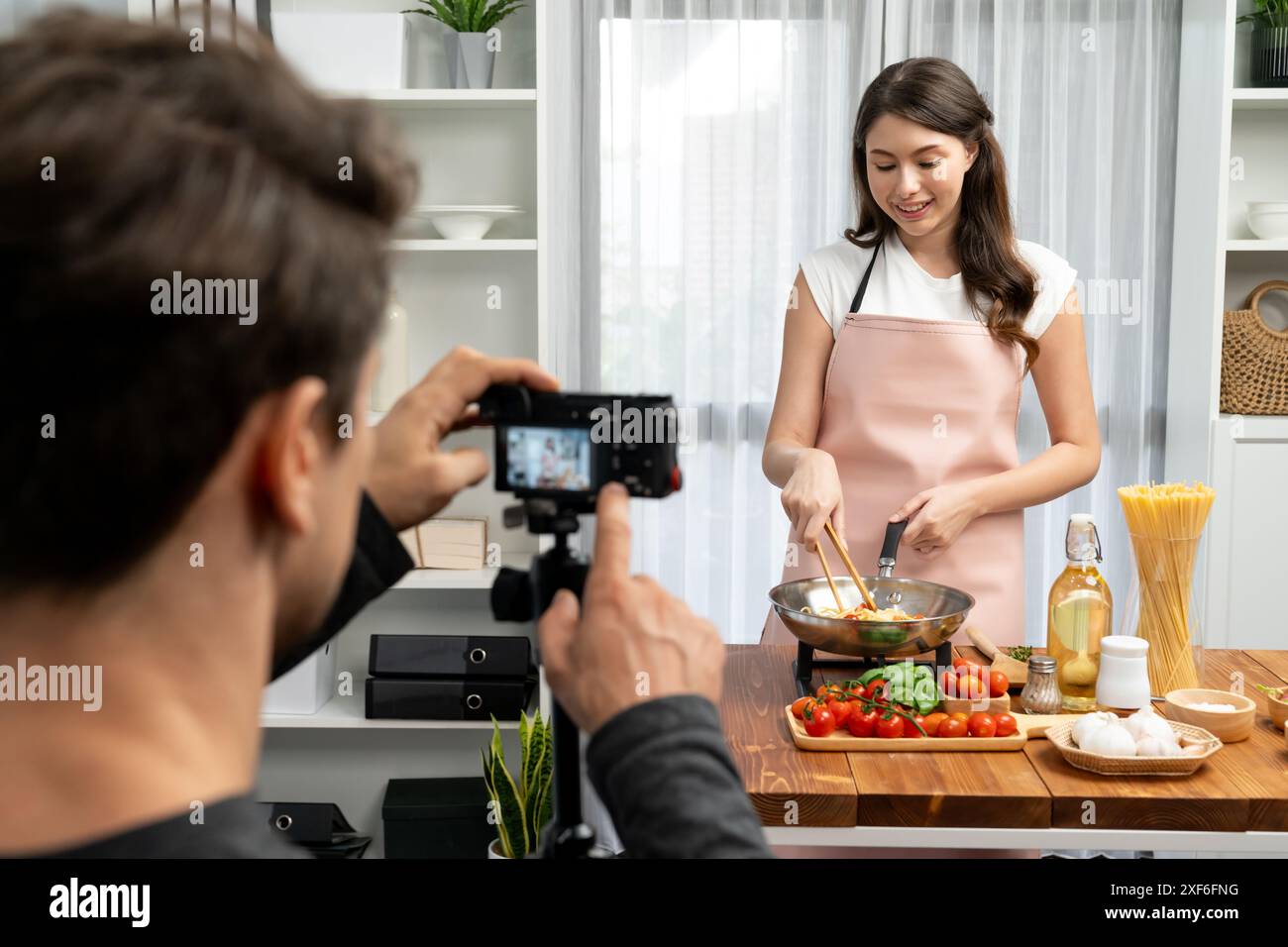 Cameraman recording to woman in chef influencer host cooking spaghetti ...