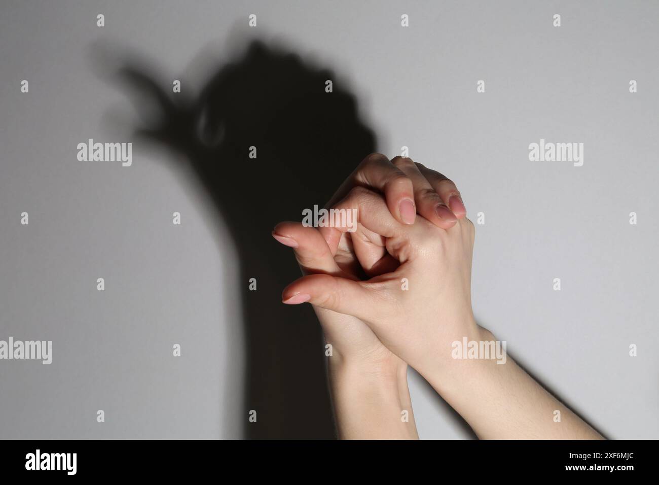 Shadow puppet. Woman making hand gesture like bird on grey background ...