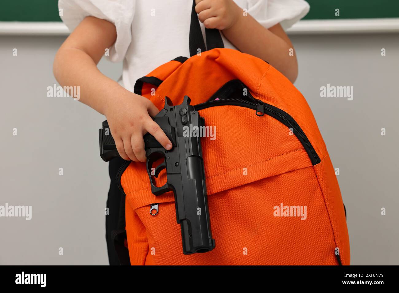 Child with gun and backpack in classroom, closeup. School shooting ...