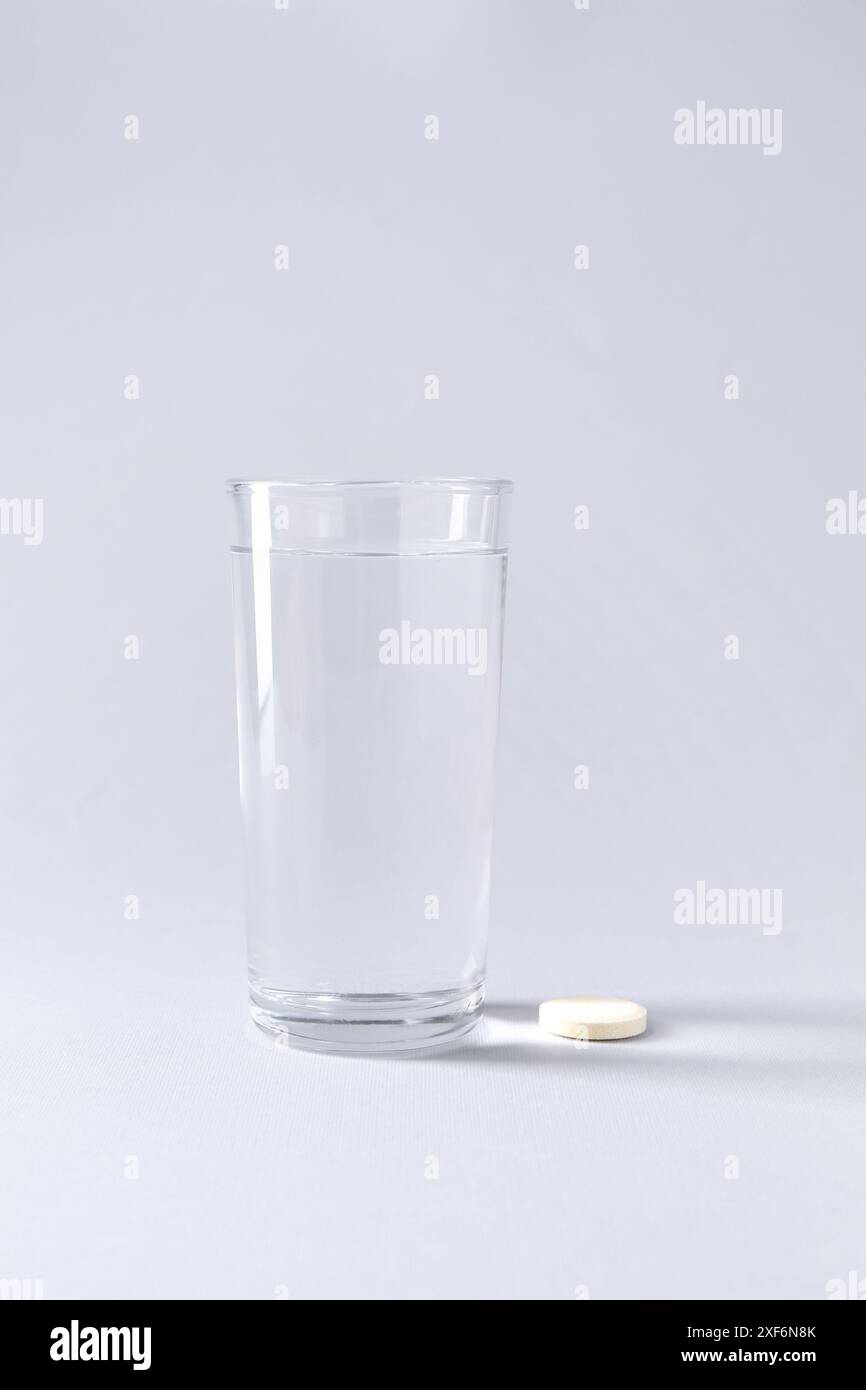 Effervescent pill and glass of water on light grey background Stock ...