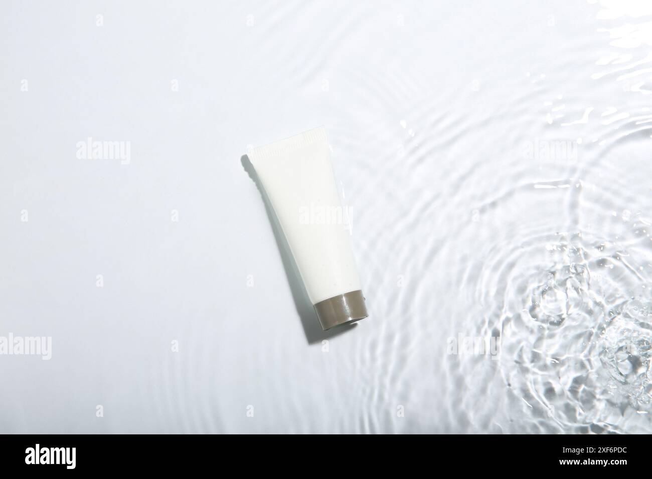Cosmetic product. Tube with cream in water on light background, top ...