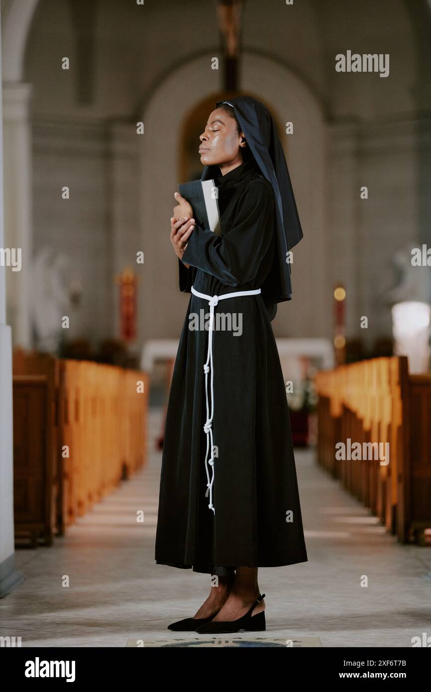 Vertical long shot young African American nun holding Bible book ...