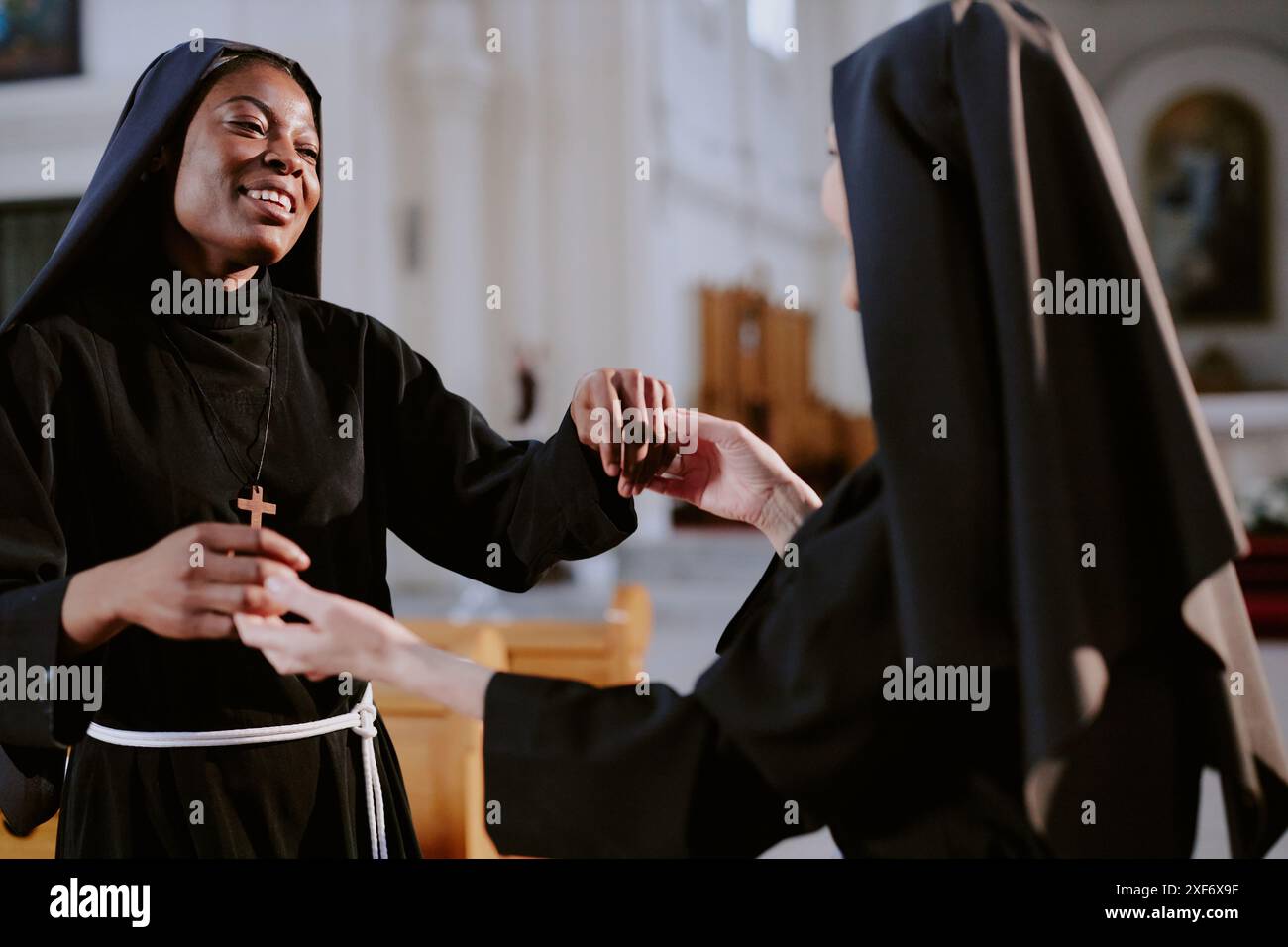 Young African American and mature Caucasian Catholic nuns having fun ...
