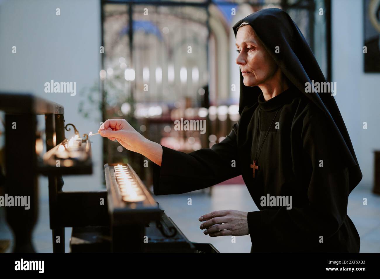 Medium shot of mature Caucasian Catholic nun holding burning match ...