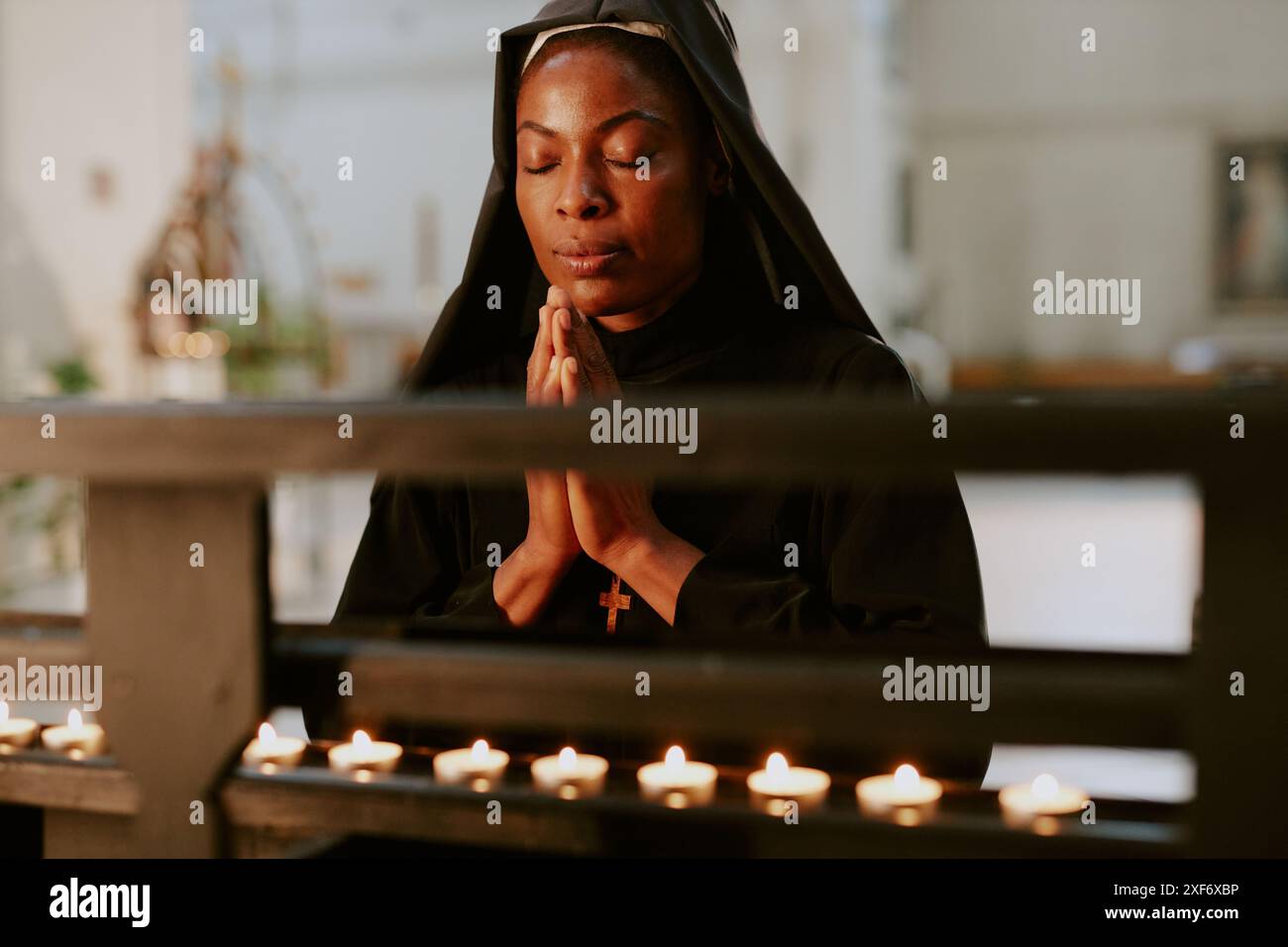 Young African American Catholic nun standing in front of altar with ...