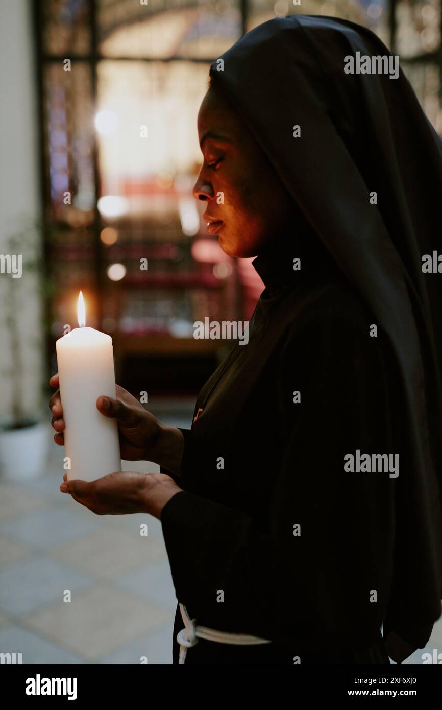 Vertical side view of young African American Catholic nun holding ...