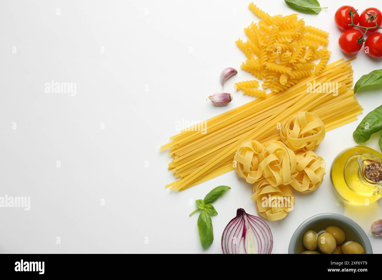 Different types of pasta, spices and products on white background, top ...