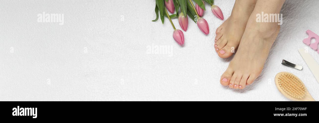 Woman showing neat toenails after pedicure procedure and flowers on ...