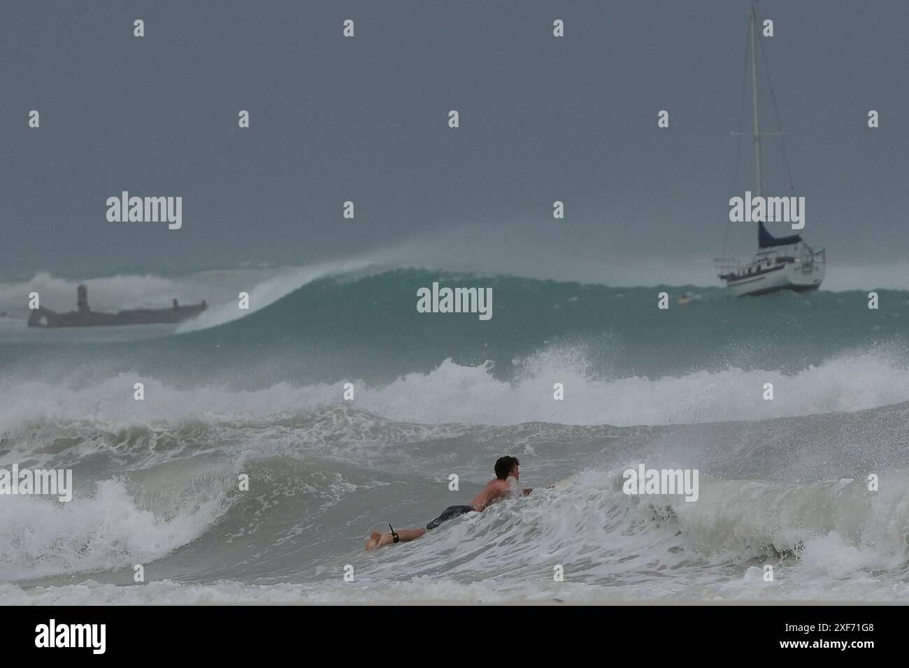 A surfer braves the waves in Carlisle Bay as Hurricane Beryl passes ...