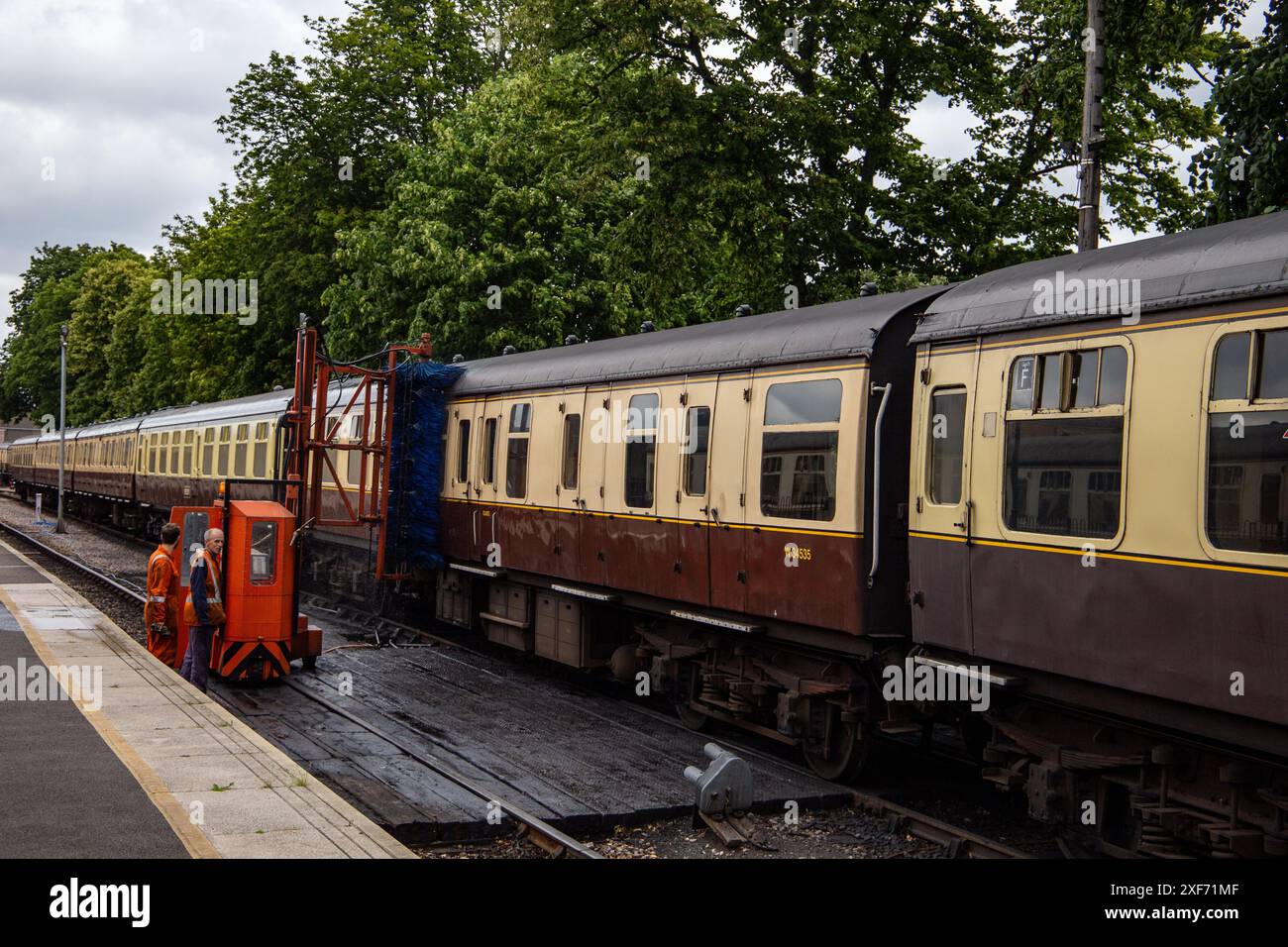 Vintage train carriages at a station platform being cleaned by a ... Vintage train carriages at a station platform being cleaned by a ...