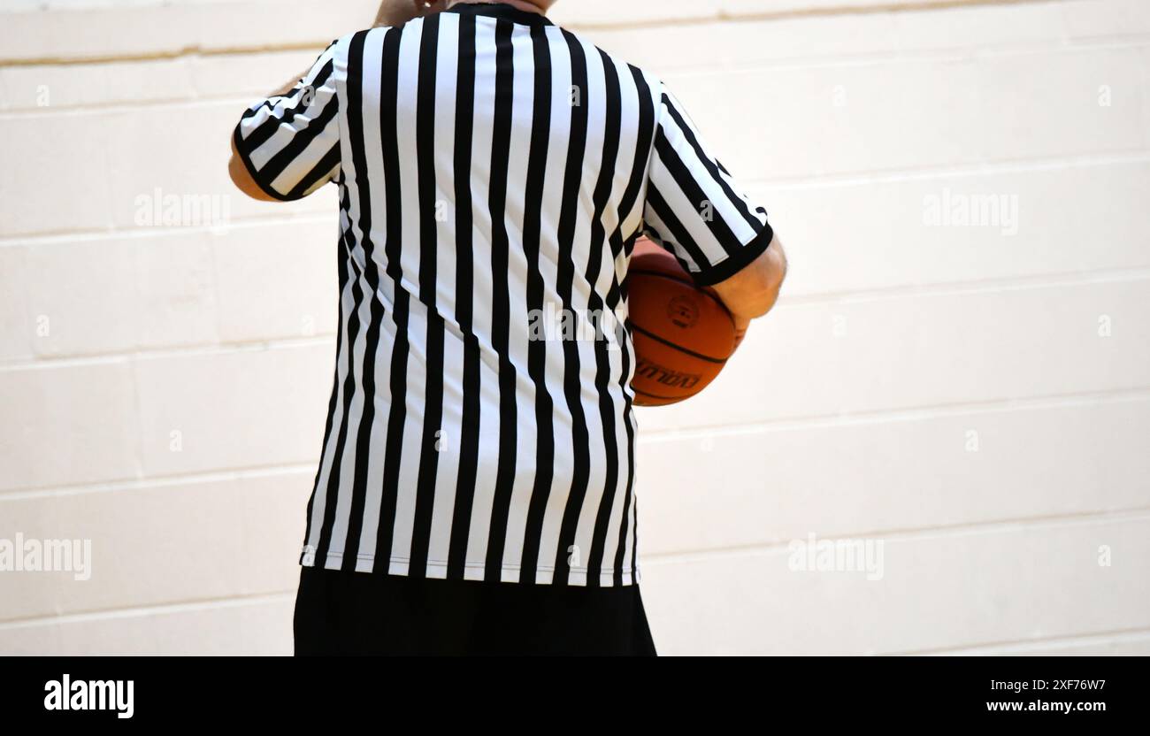 Referee holds a basketball, in the crook of his elbow, during a time ...