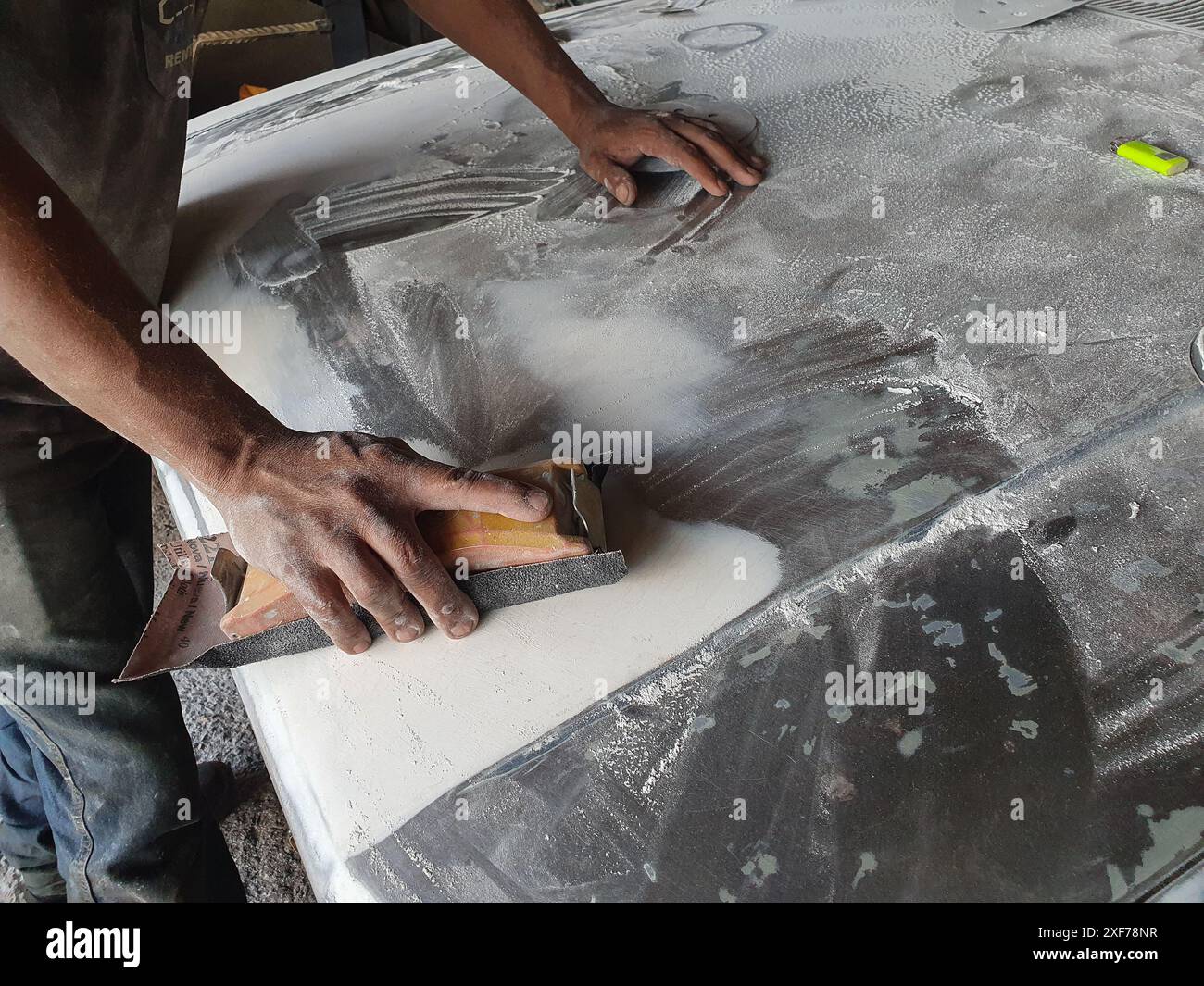 A worker, mechanic and tinsmith, with his hands, sanding the hood of an ...
