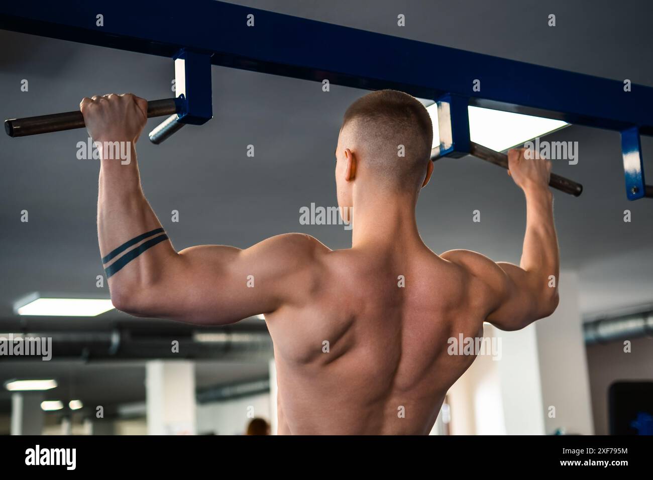 Bodybuilder performs a pull-up exercise at a gym, showcasing his ...