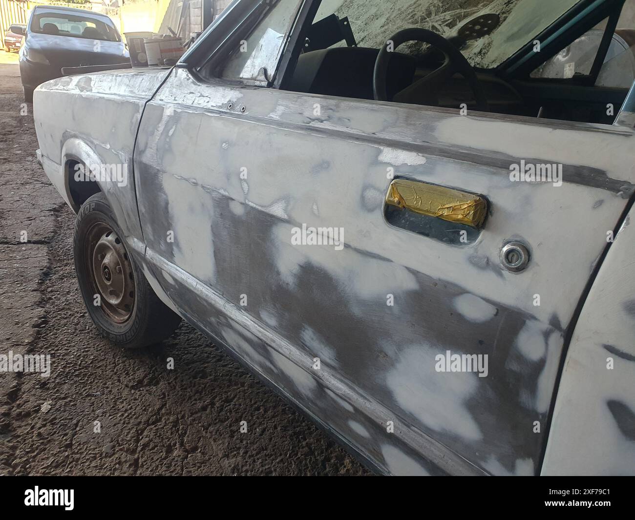 Side of an old car, closed door and open window, sanded and putty ...