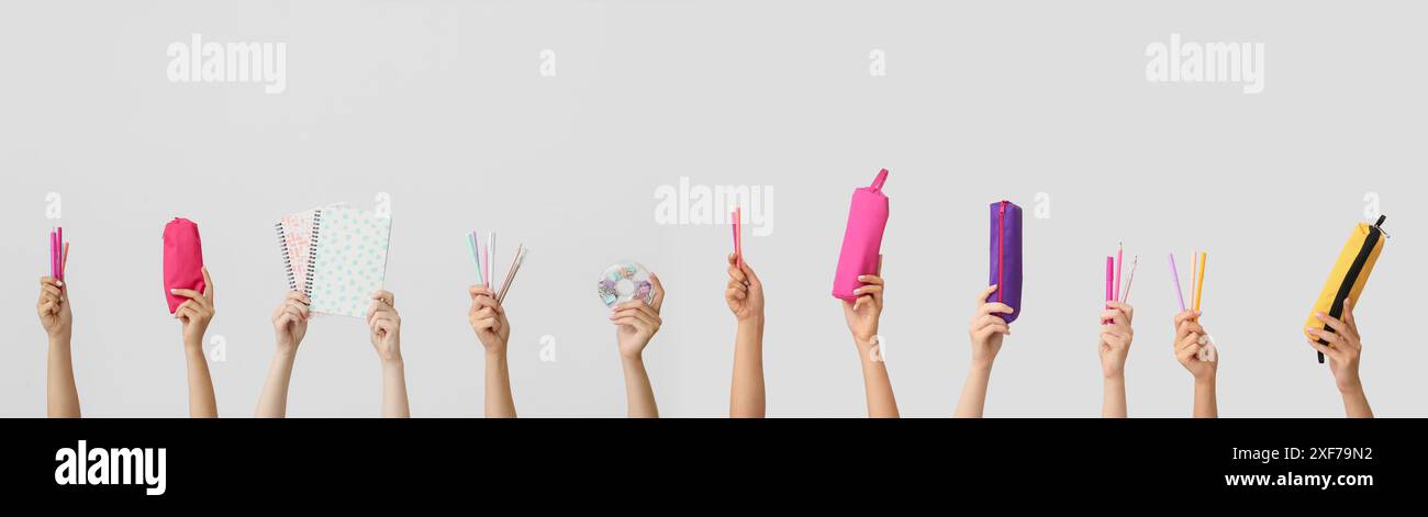 Many hands with school supplies on light background Stock Photo - Alamy