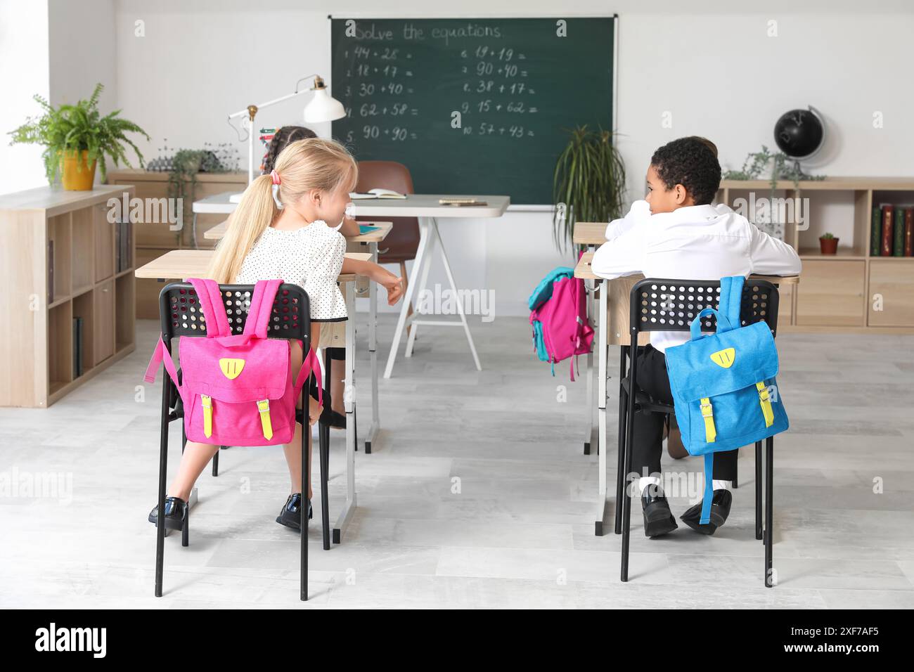 Little classmates sitting at desks in classroom during lesson Stock ...