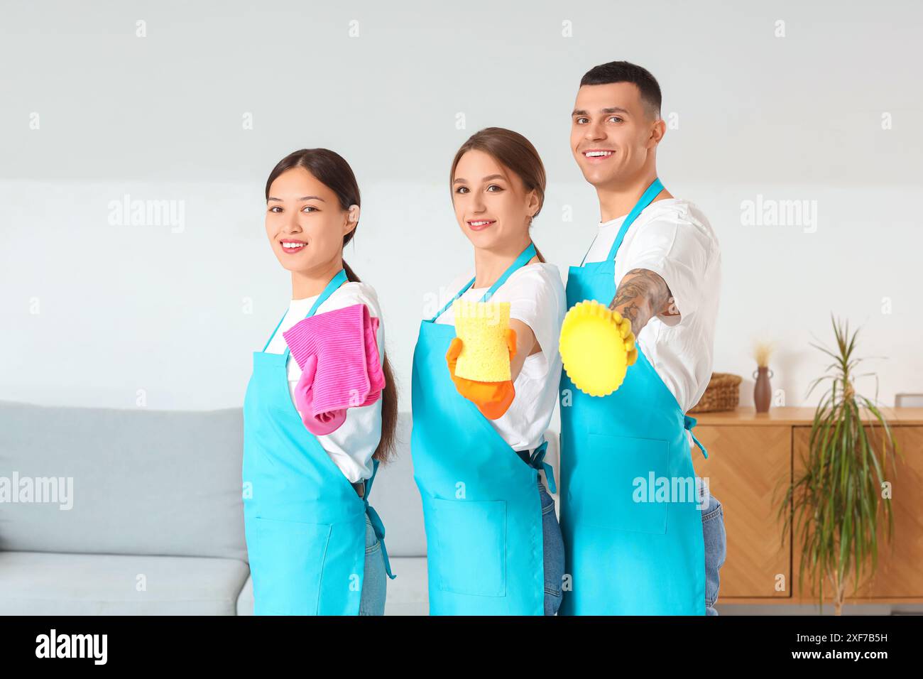 Team of young janitors with cleaning supplies in room Stock Photo - Alamy