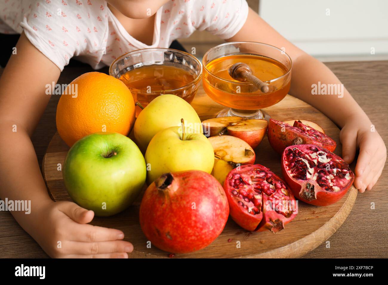 Cute little girl with ripe fruits and honey in kitchen, closeup. Rosh ...