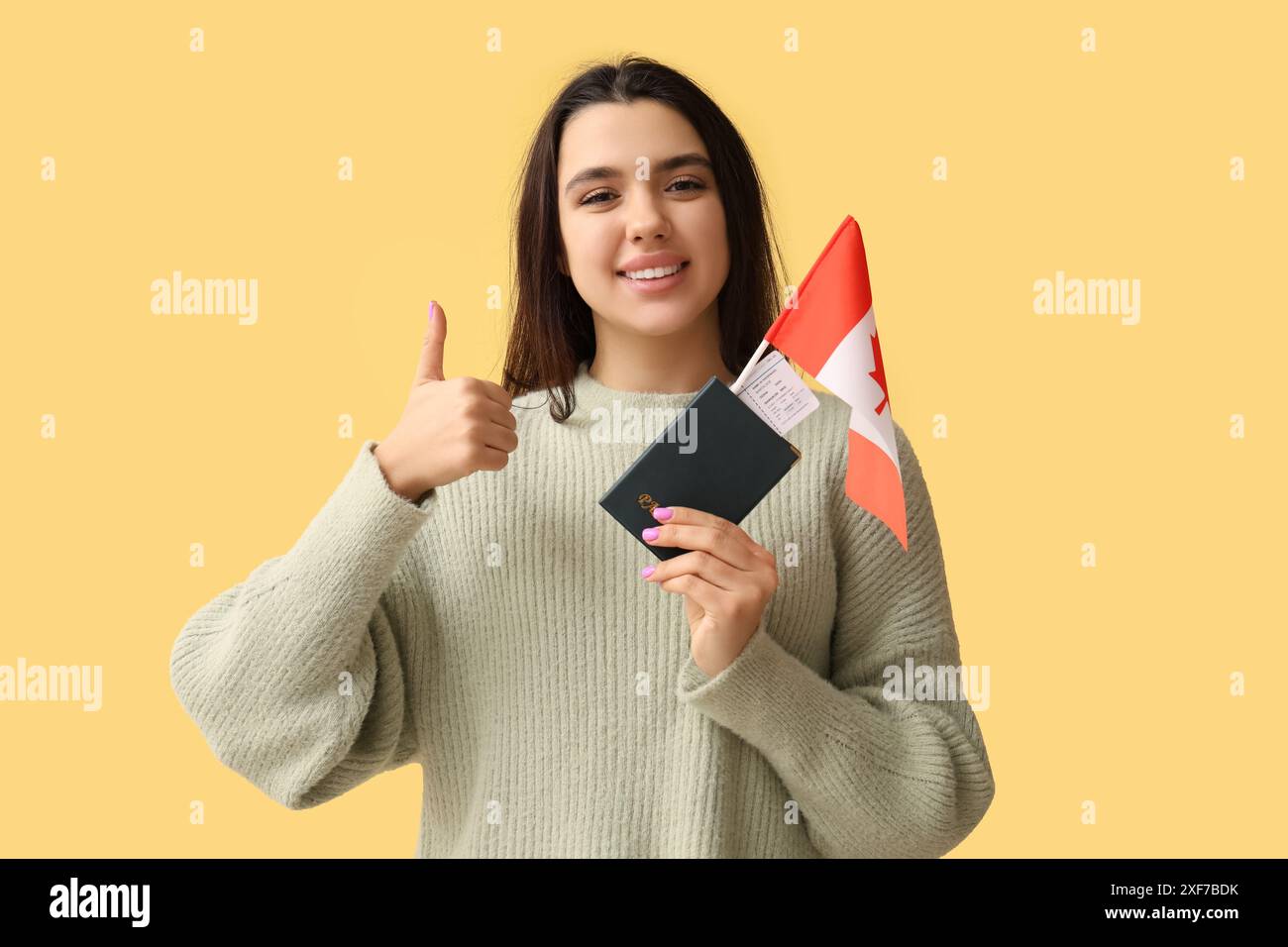 Beautiful young happy woman with Canadian flag, passport and ticket ...