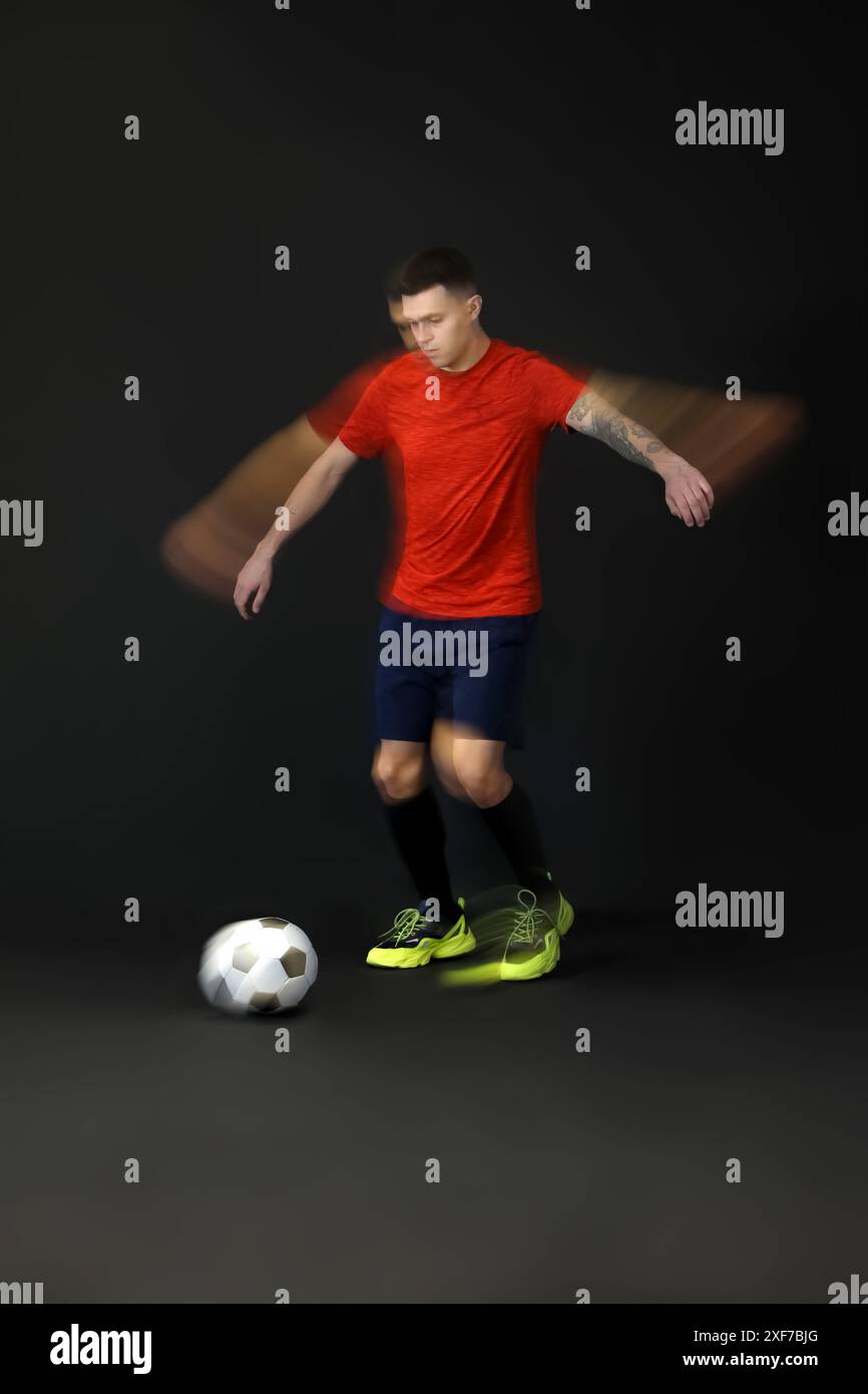 Male footballer playing with ball in motion on black background Stock ...