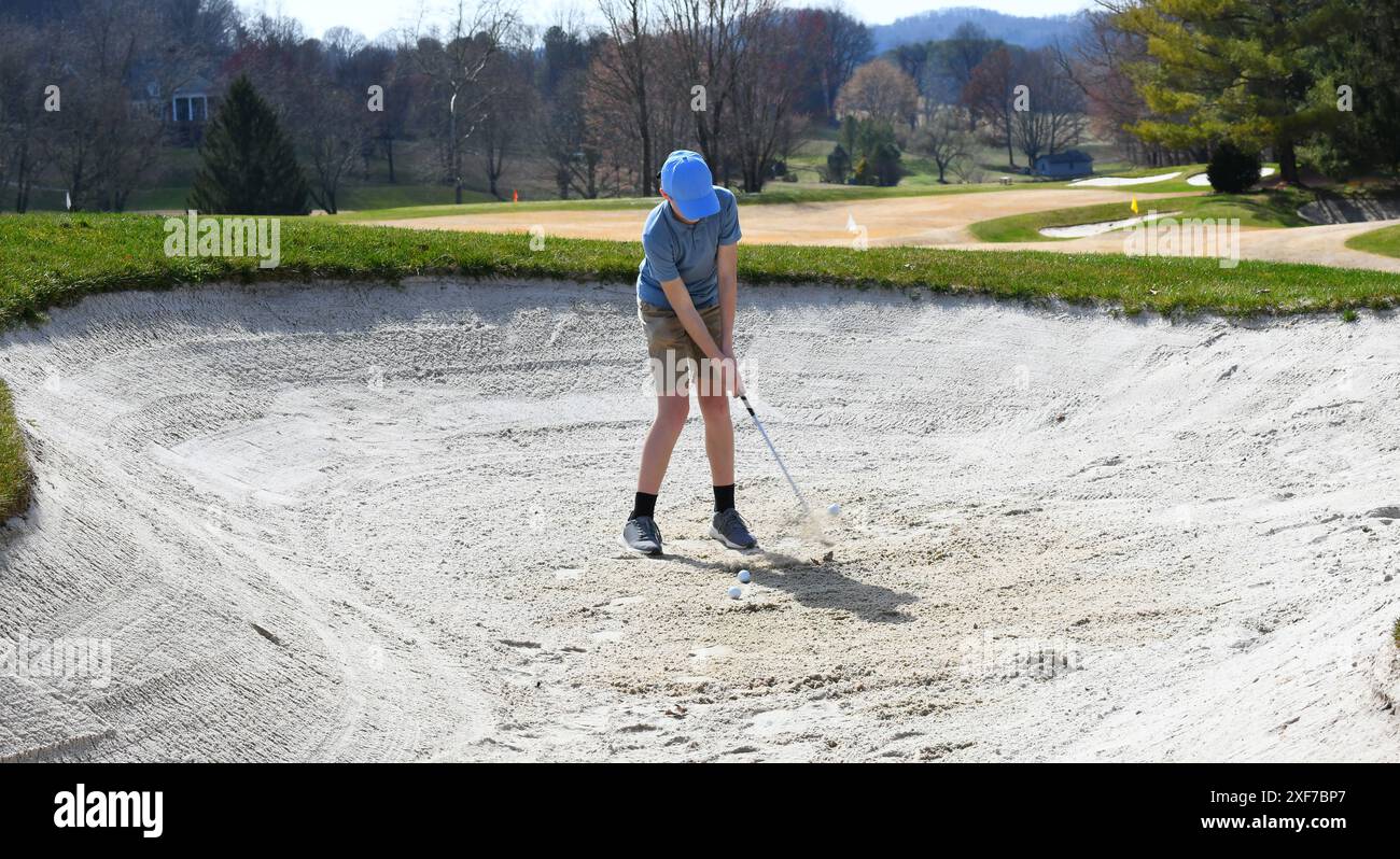 Teen varsity player, practices chipping out of a sand trap on a golf ...